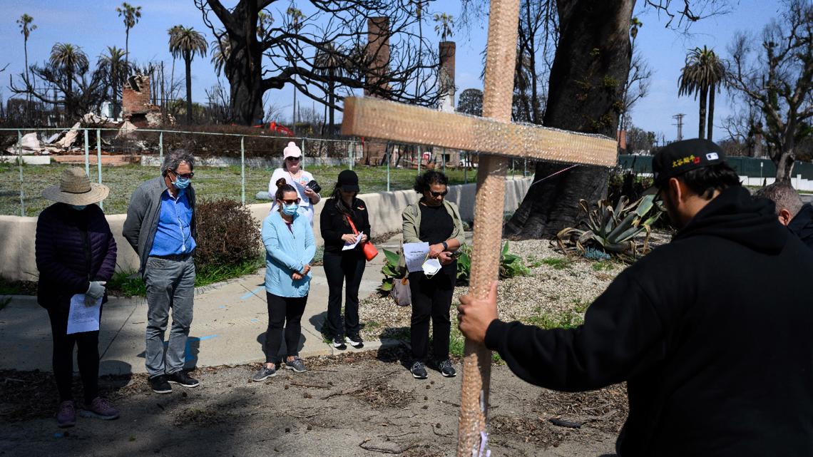 Members of burned LA church bear a cross through their devastated ...